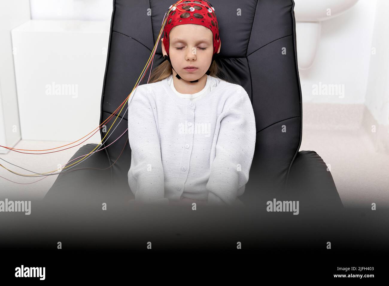 Patient sitting on a chair with eyes closed during a biofeedback ...