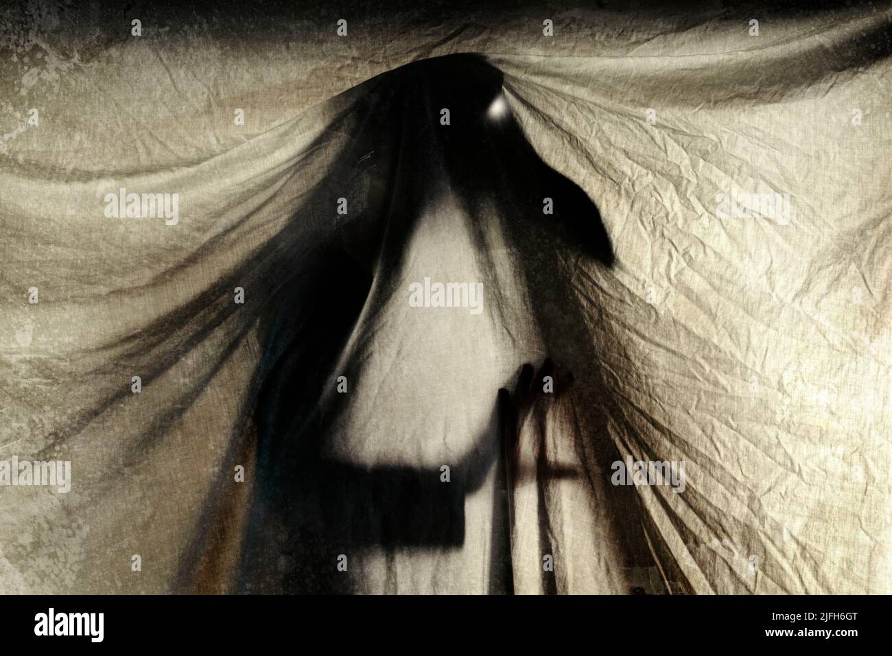 A scary horror of a demonic figure silhouetted, behind a curtain. With ...