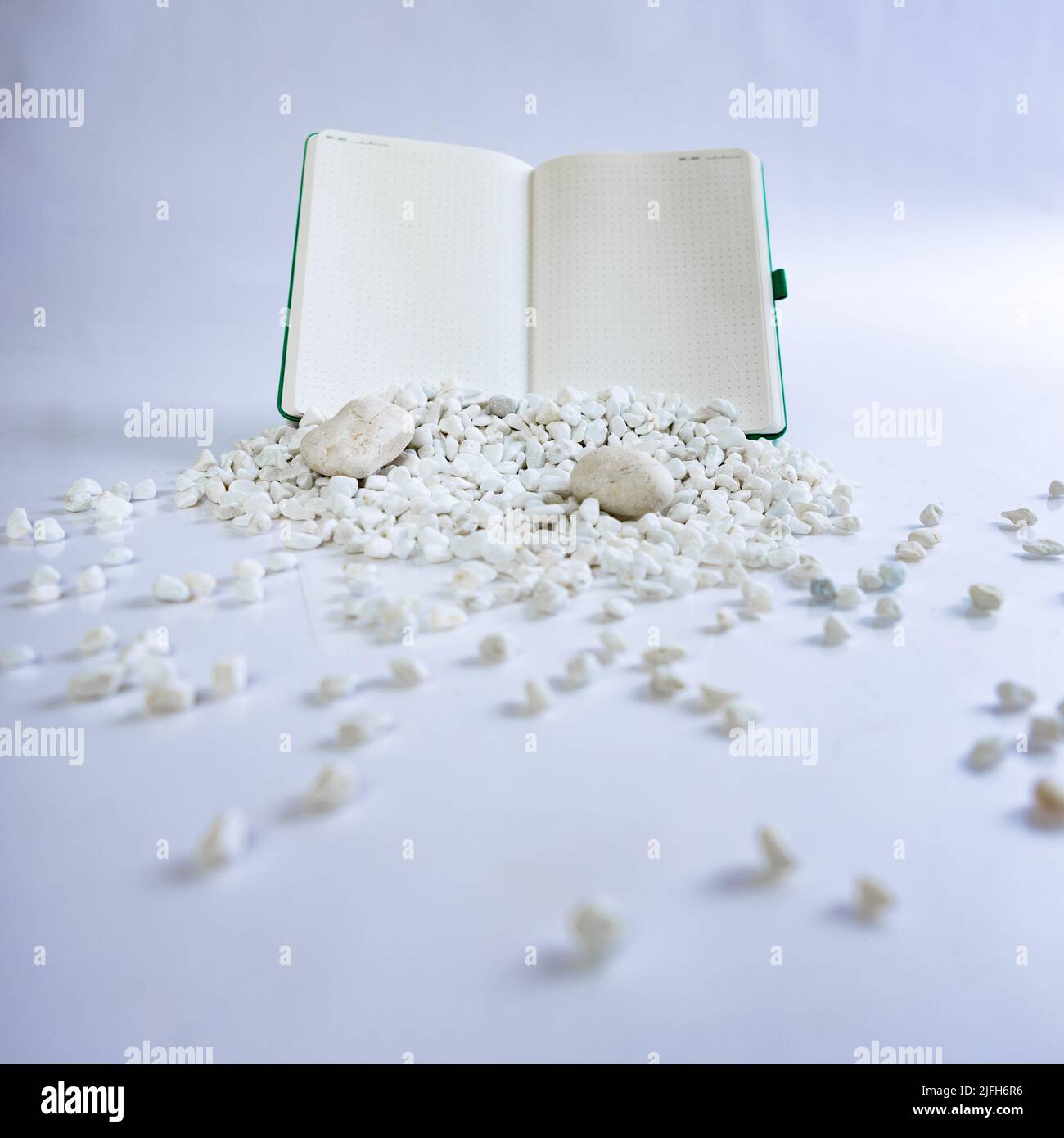 Notebook on white studio background. White rocks falling in front of it ...