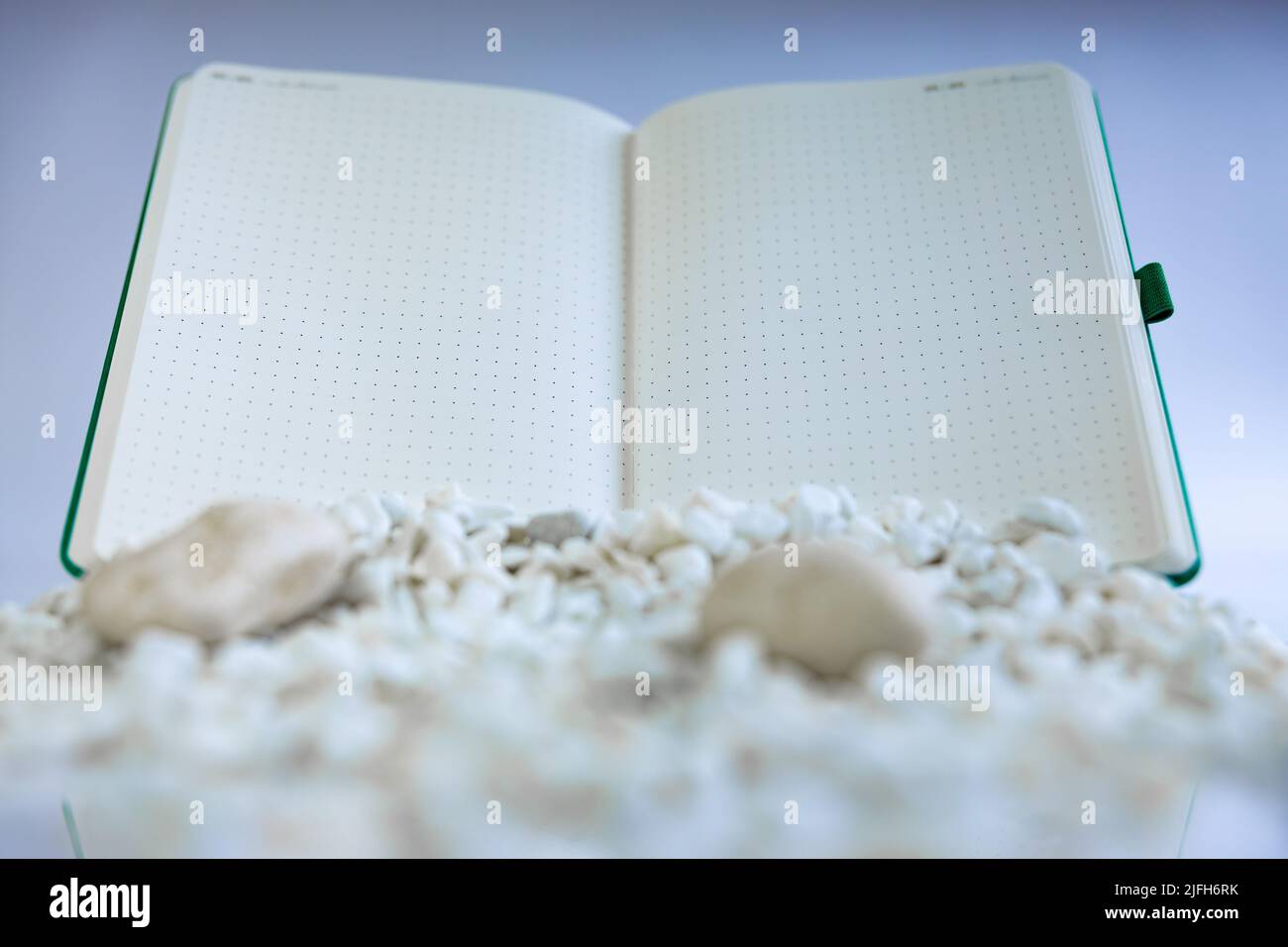 Notebook on white studio background. White rocks falling in front of it ...