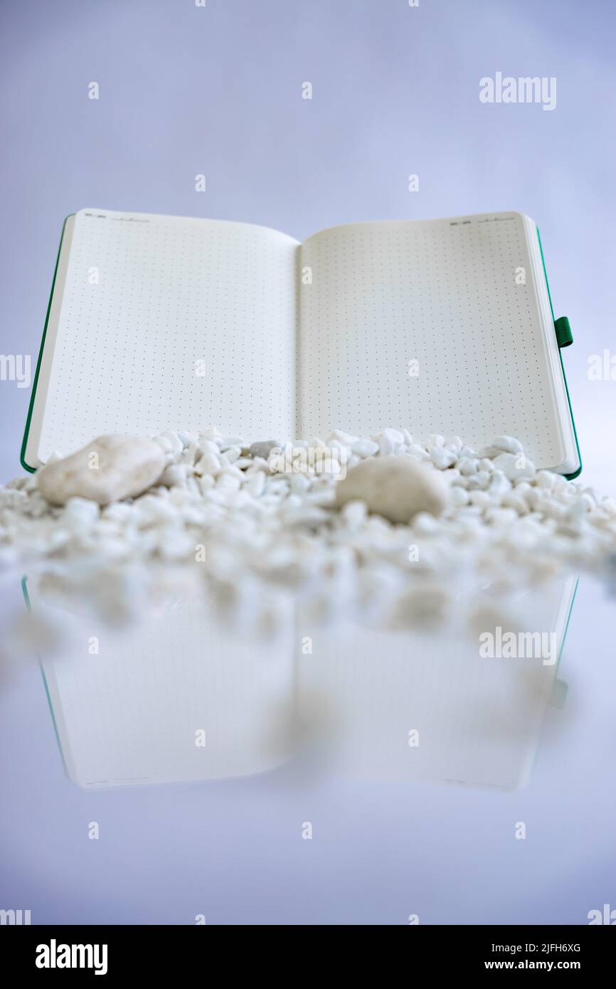 Notebook on white studio background. White rocks falling in front of it ...