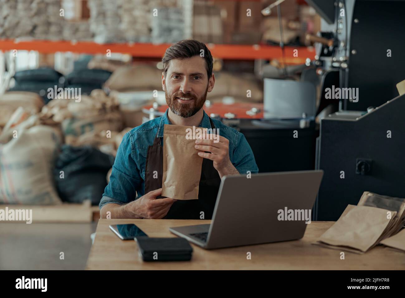 Business owner holding roasted coffee beans in paper bag in coffee ...