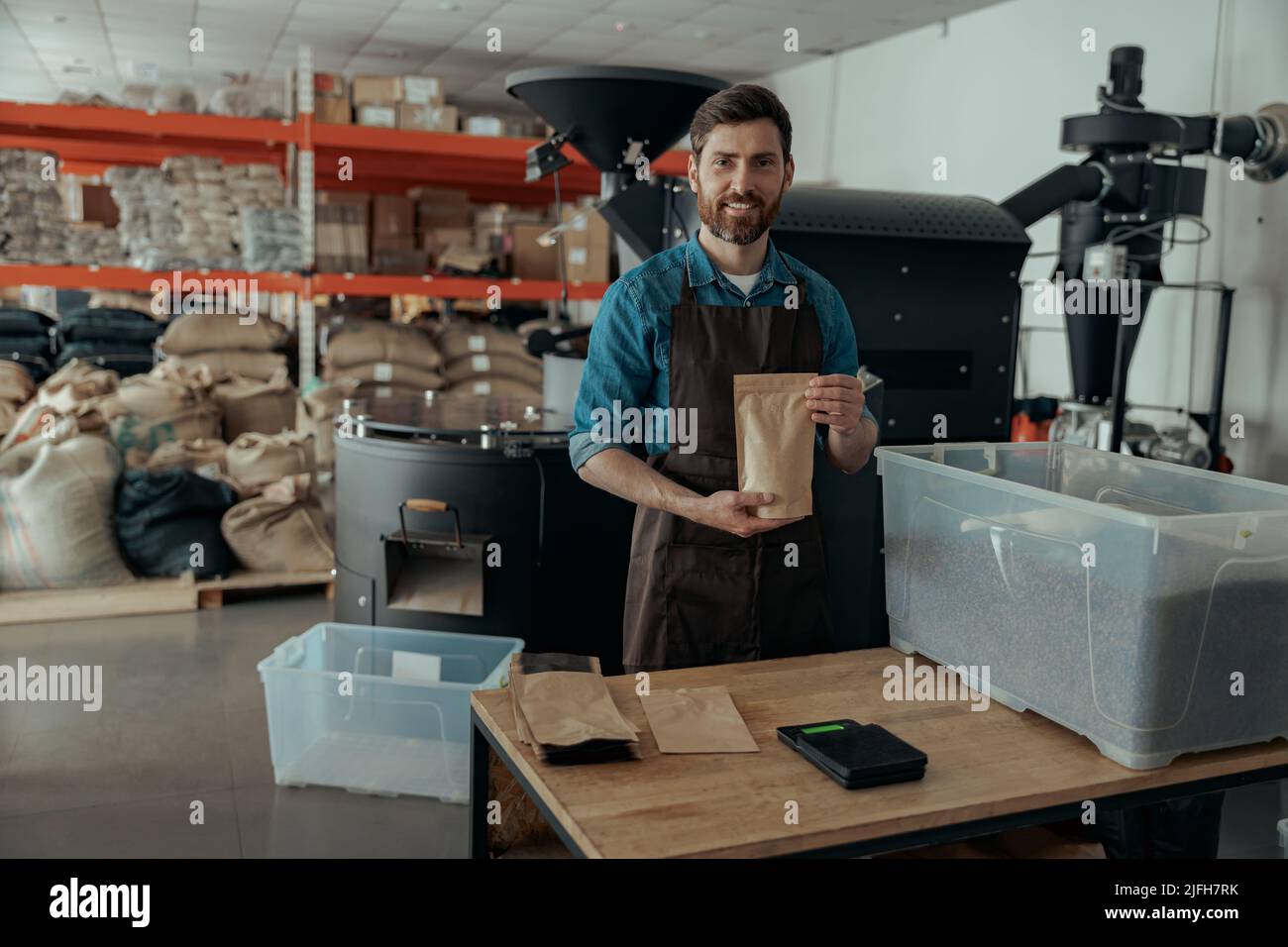 Business owner holding roasted coffee beans in paper bag in coffee ...