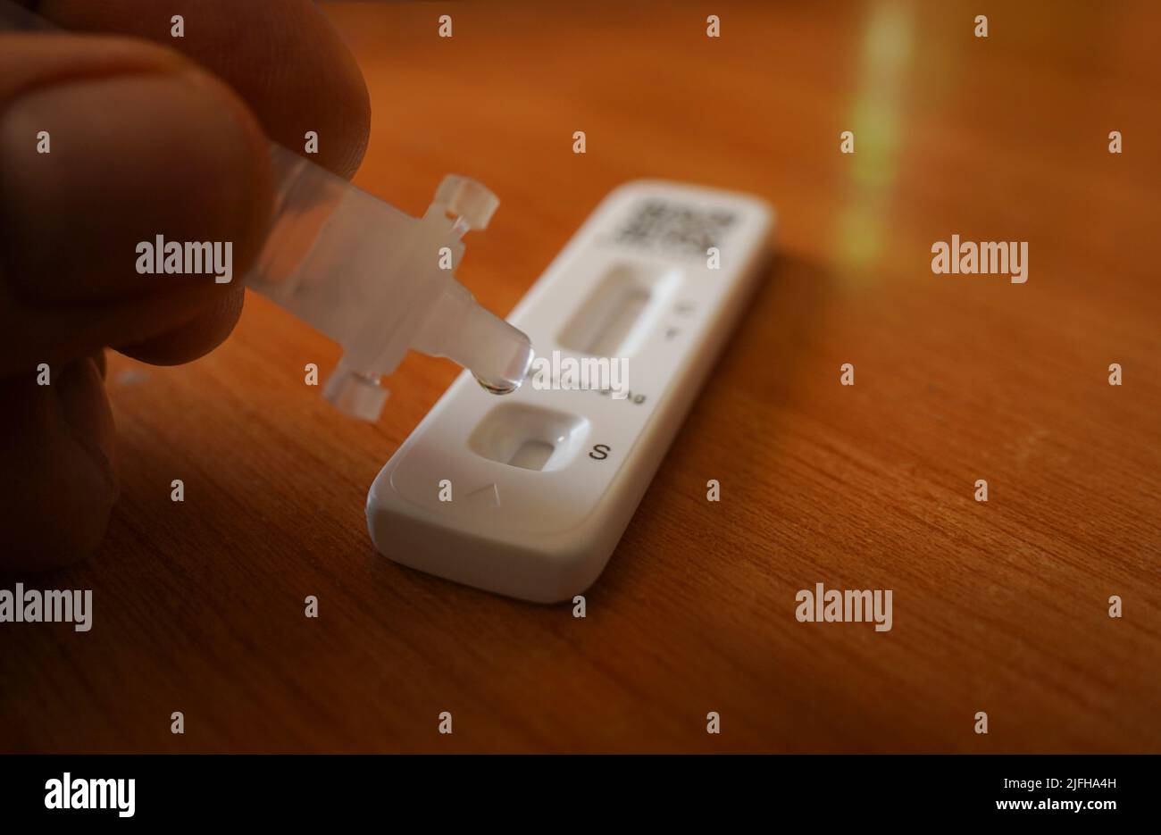 A covid swab sample in solution is dropped onto the test cassette of a ...