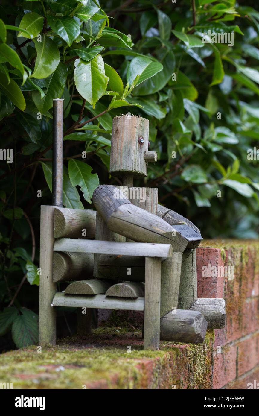 A wooden garden character sat on a garden seat Stock Photo - Alamy