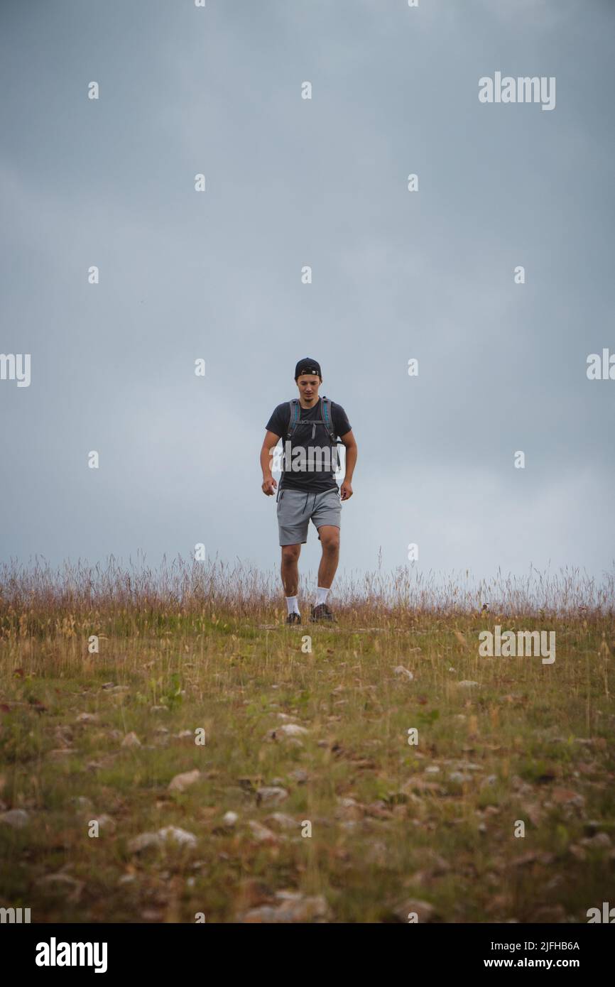 Swarthier type of man is running down a gravel hill, checking his every ...