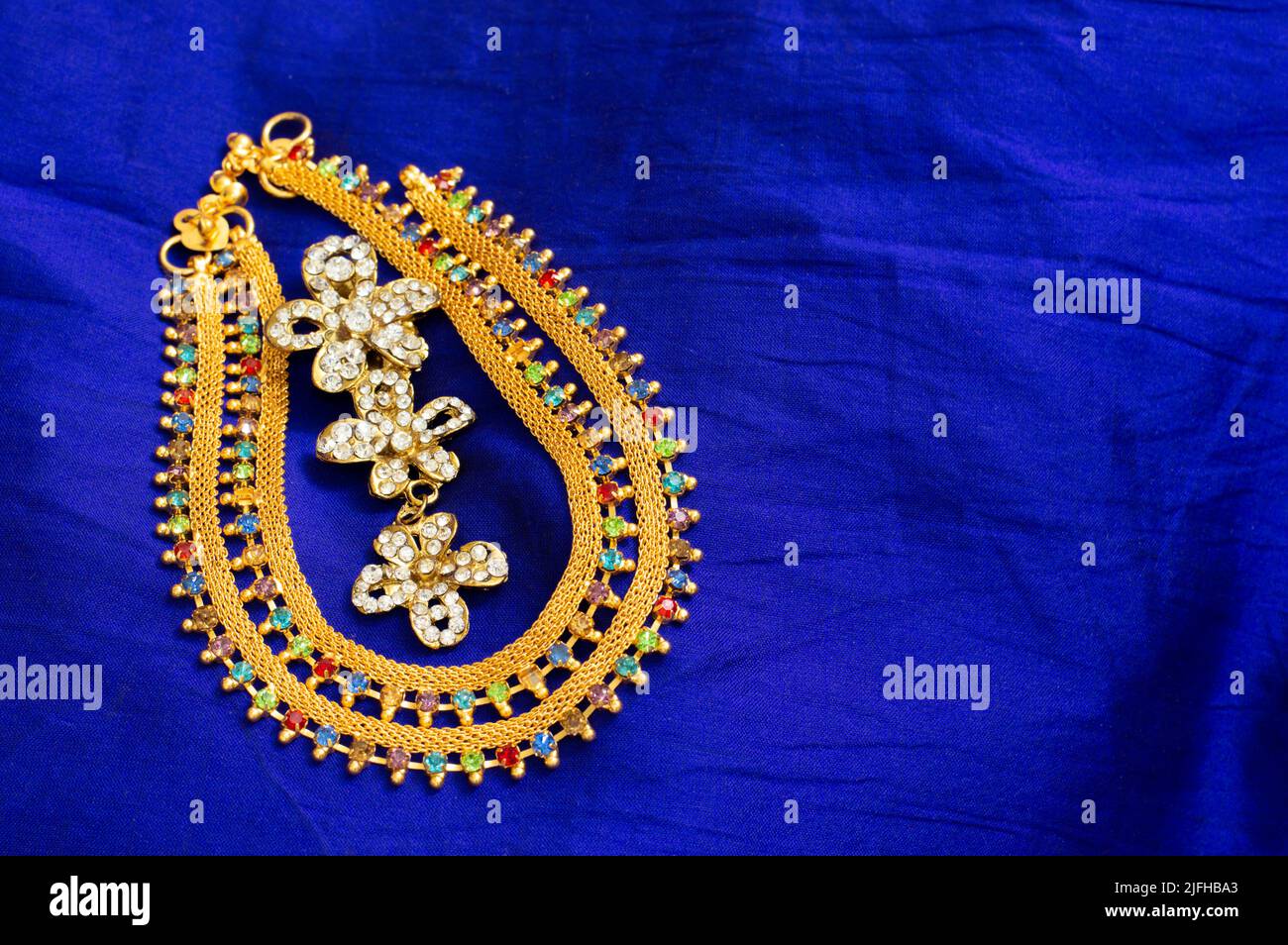 Indian leg wear jewellery Payal with colorful stone on blue background ...