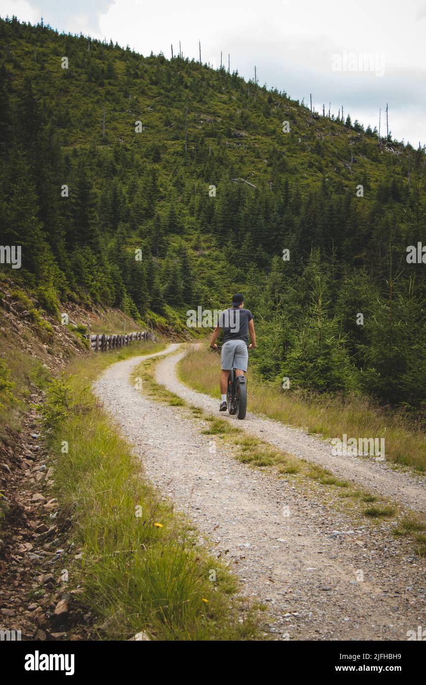 Swarthier type of person rides a downhill mountain scooter on a steep ...