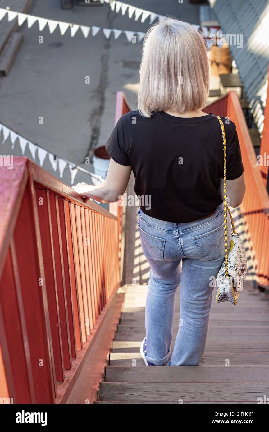 girl standing on the stairs holding on to the red railing. High quality ...