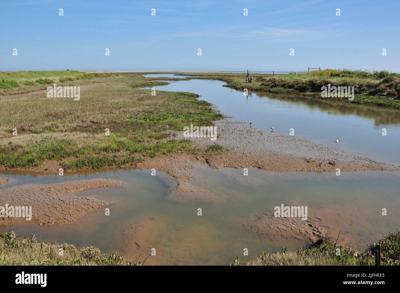A calm ebbing tide amid marshland at Thornham, Norfolk, England, UK ...