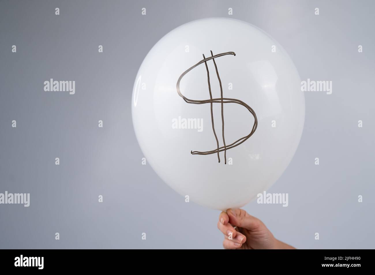 A woman is holding a balloon with a dollar sign. The concept of an ...