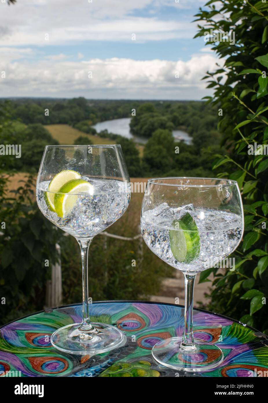 Two gin glasses, large and small, with ice cubes and slice of lime ...