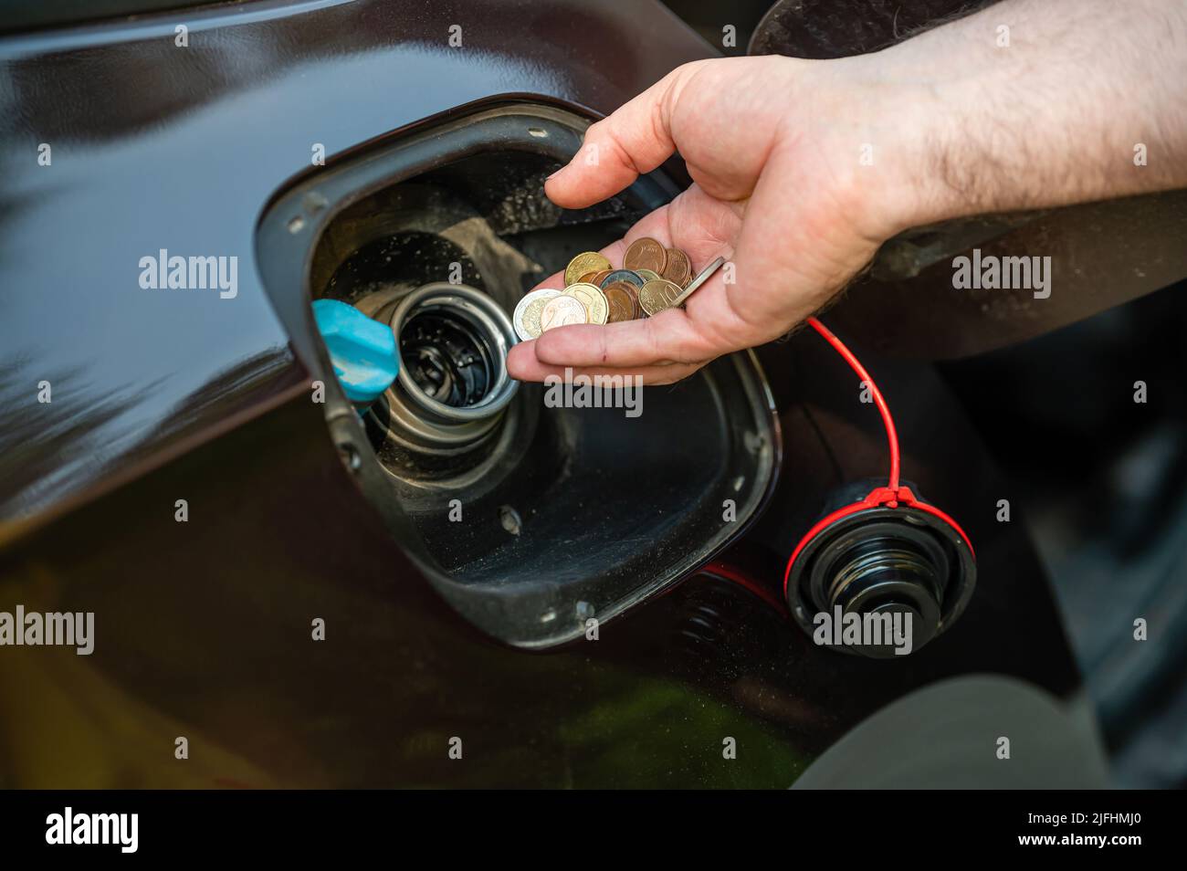 hand of man putting coins in car tank, close-up, expensive fuel concept ...
