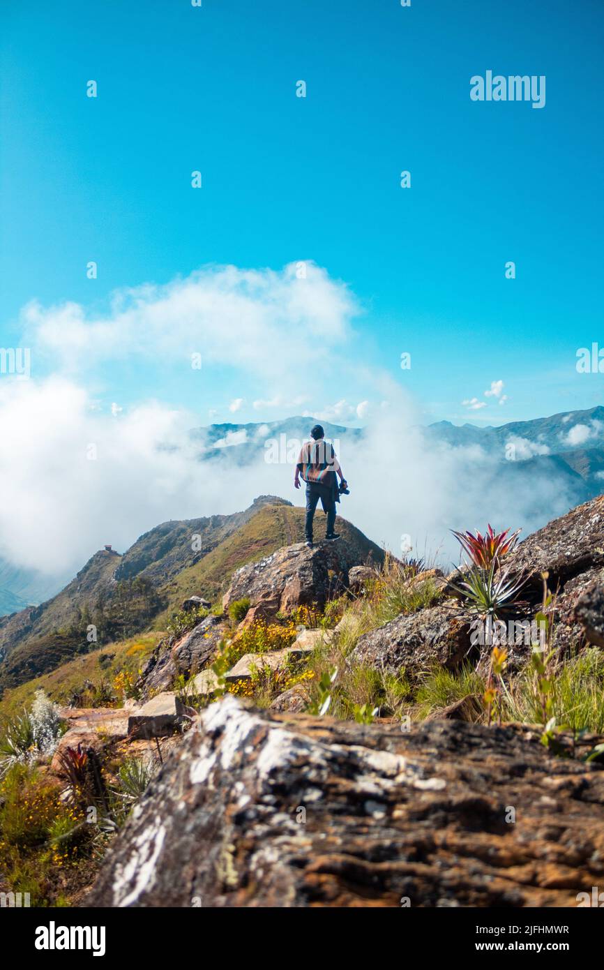 A vertical view of a man standing at a height looking at the landscape ...