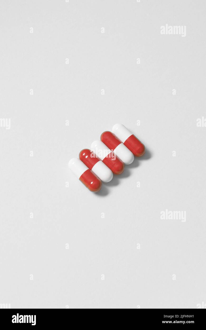 Red and white pharmaceutical tablets neatly laid over white background ...