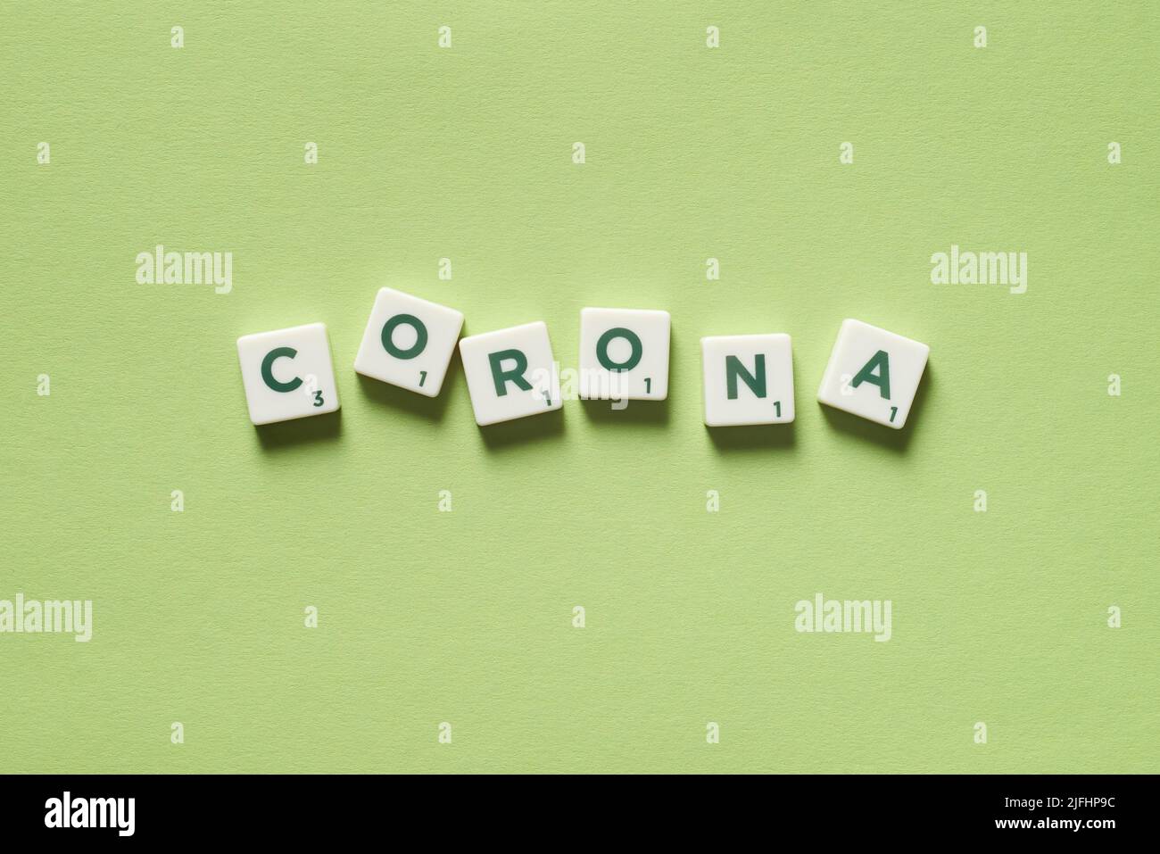 Corona word formed of messy scrabble tiles on green background ...
