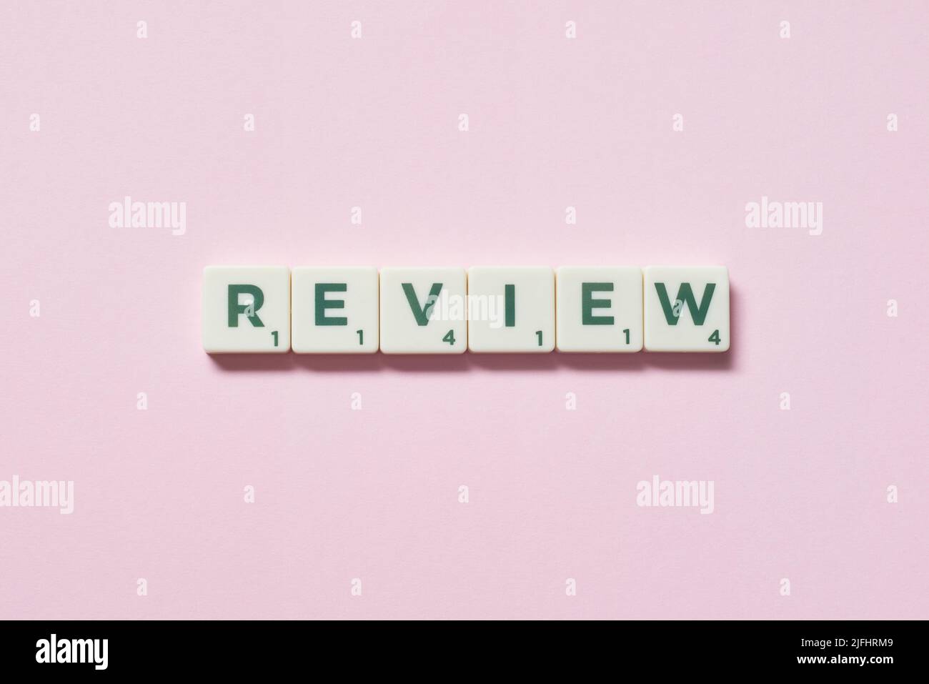 Review formed of scrabble blocks on pink background Stock Photo - Alamy