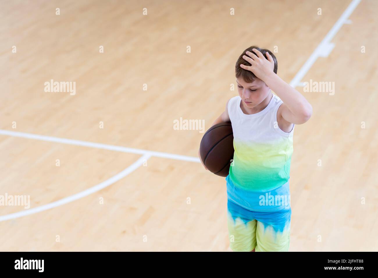 Sad disappointed boy with basketball ball in a physical education ...