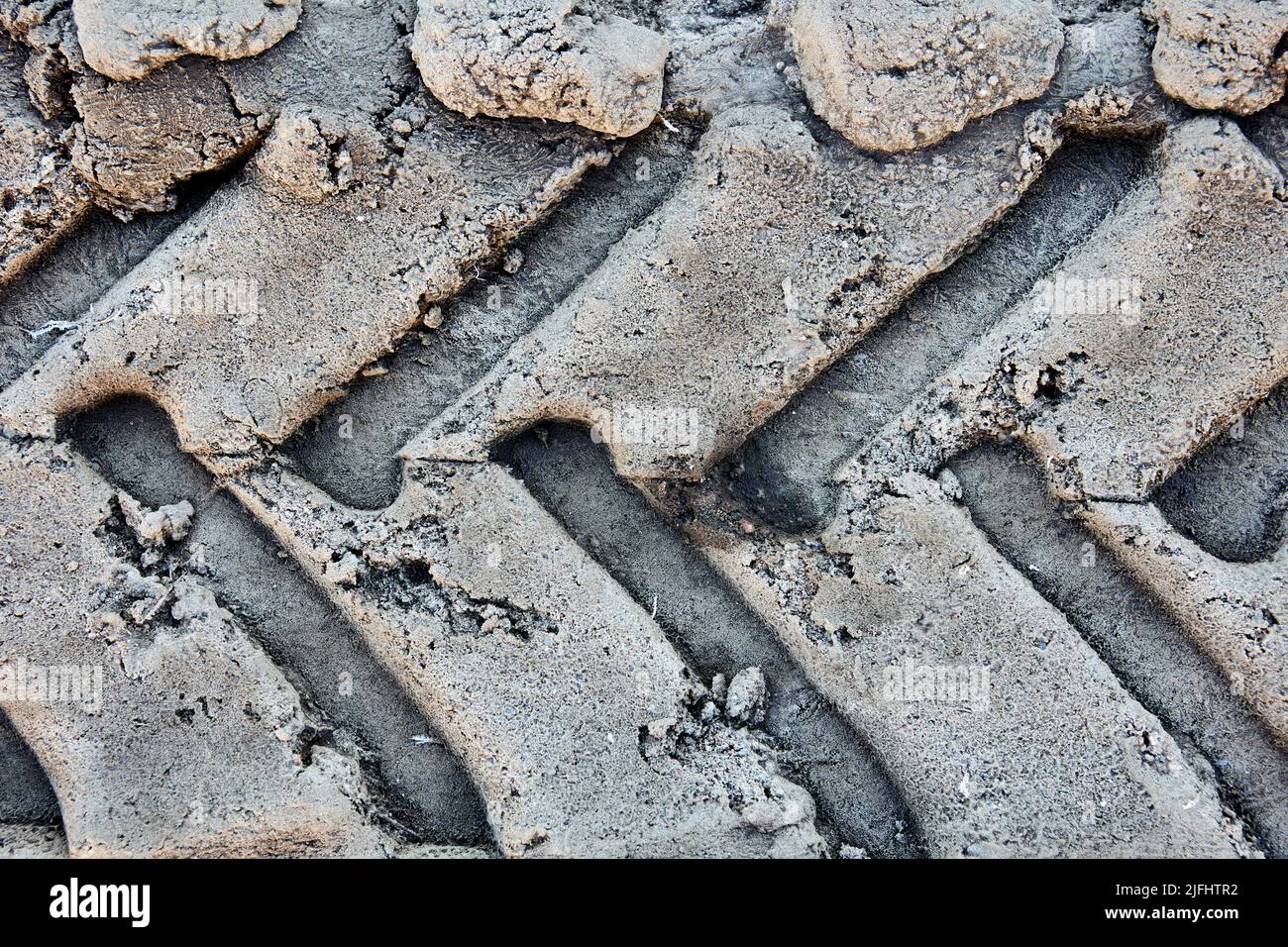 Tread tire track of wheeled tractor on wintry soil road, abstract ...