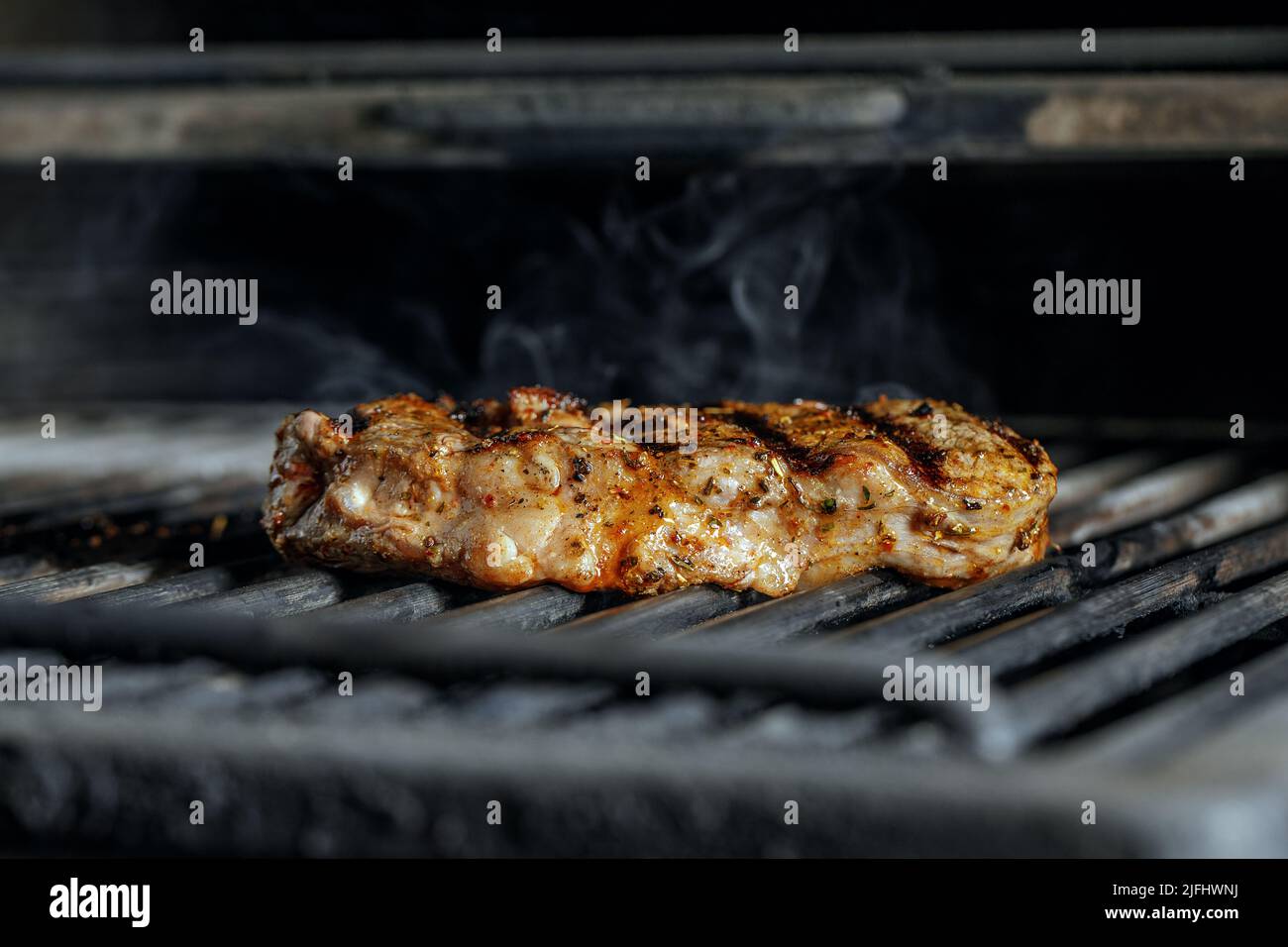 Half roasted meat beef steak grilling on rack charcoal stove with smoke ...