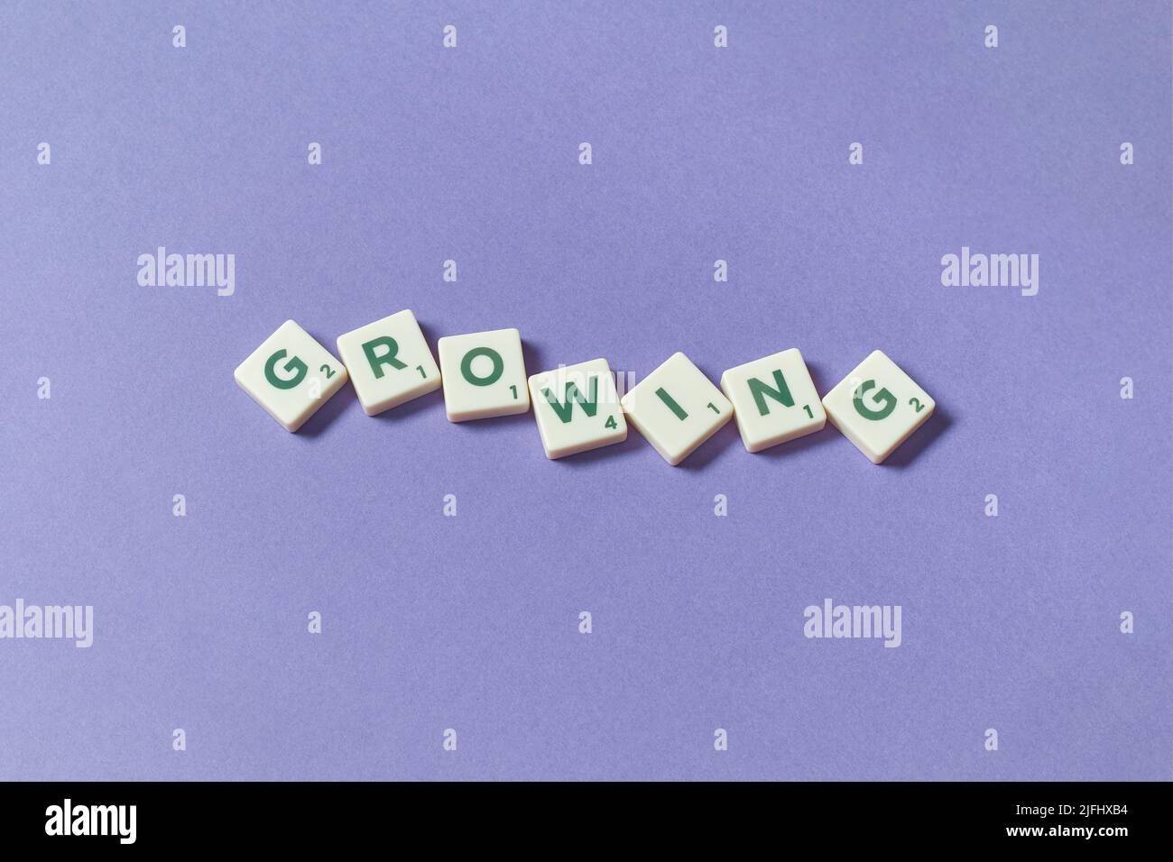 Growing formed of scrabble tiles on purple background Stock Photo - Alamy