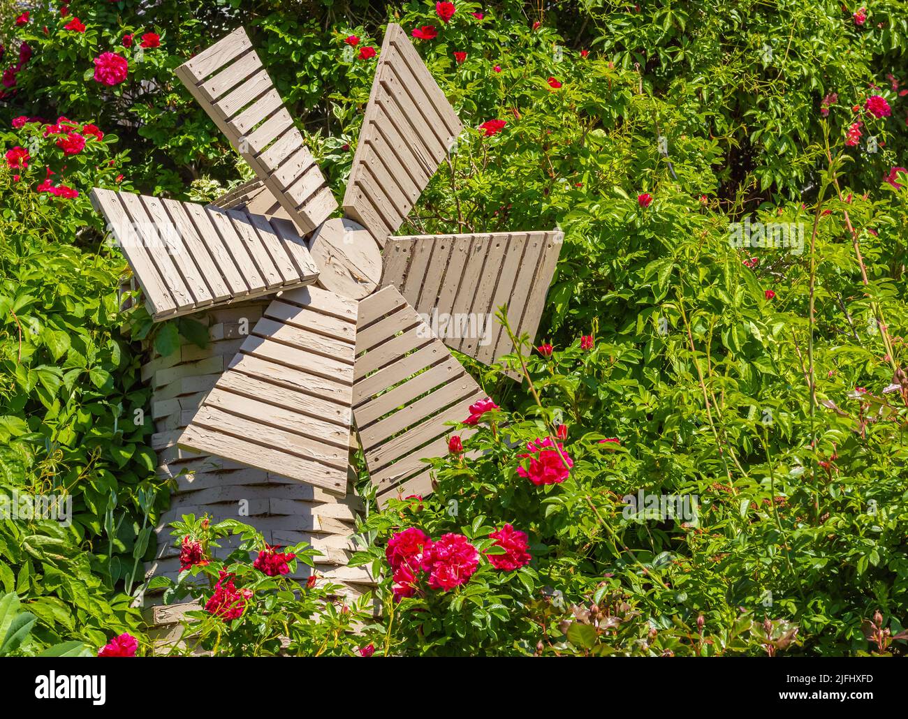 A small wooden windmill in the beautiful summer garden. Windmill and ...