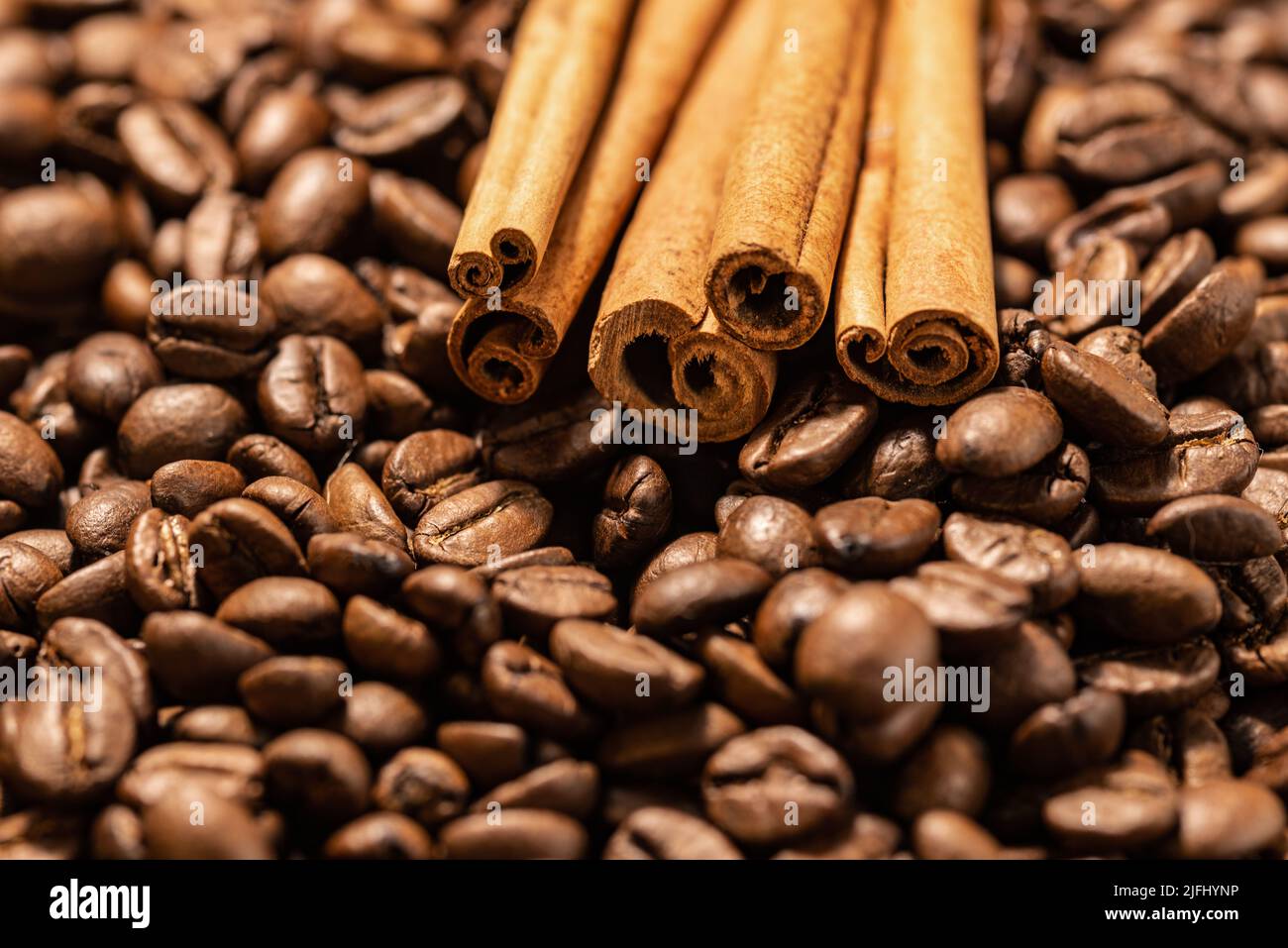 Cinnamon sticks on a background of freshly roasted coffee beans. Coffee ...