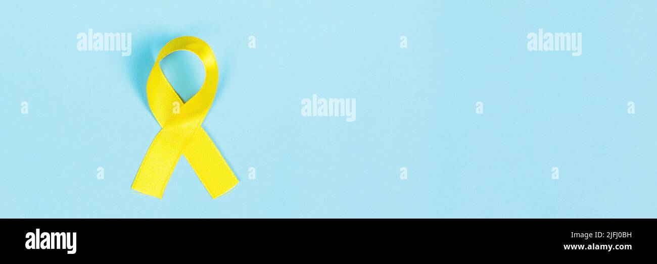 Yellow gold ribbon on a yellow background. Children cancer concept ...