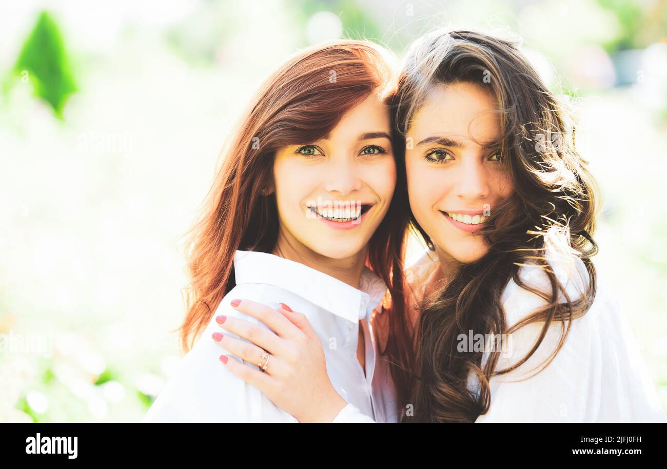 Girl friends laughing and hugging outdoors. Two women are hugging on ...
