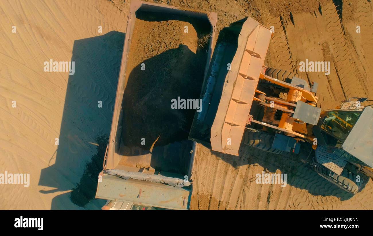 Excavator removing sand into dump truck. Scene. Top view of excavator ...