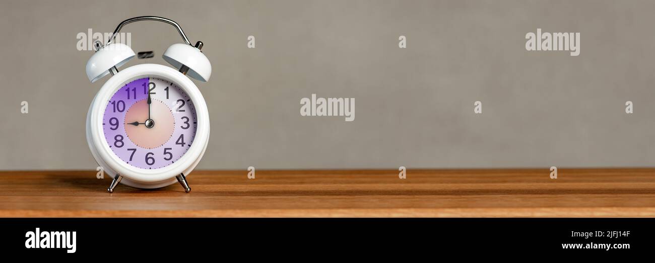 Nine o'clock on the alarm. A white alarm clock stands on a wooden table ...
