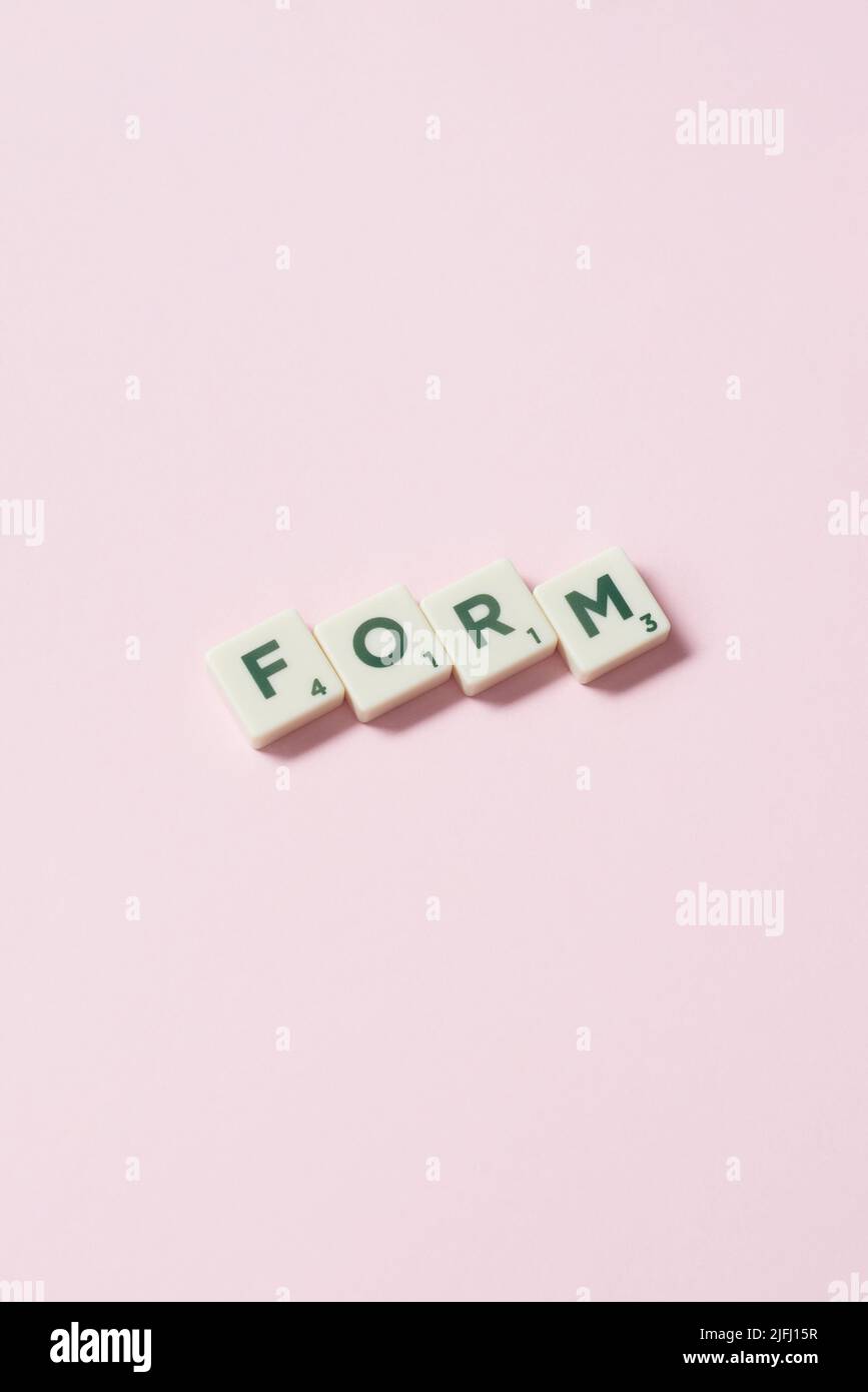 Form formed of scrabble tiles on pink background Stock Photo - Alamy