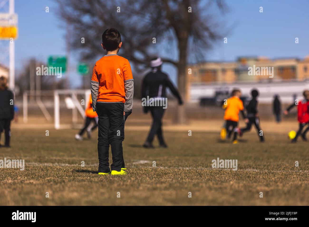 A boy from behind in the background of young soccer players playing on ...