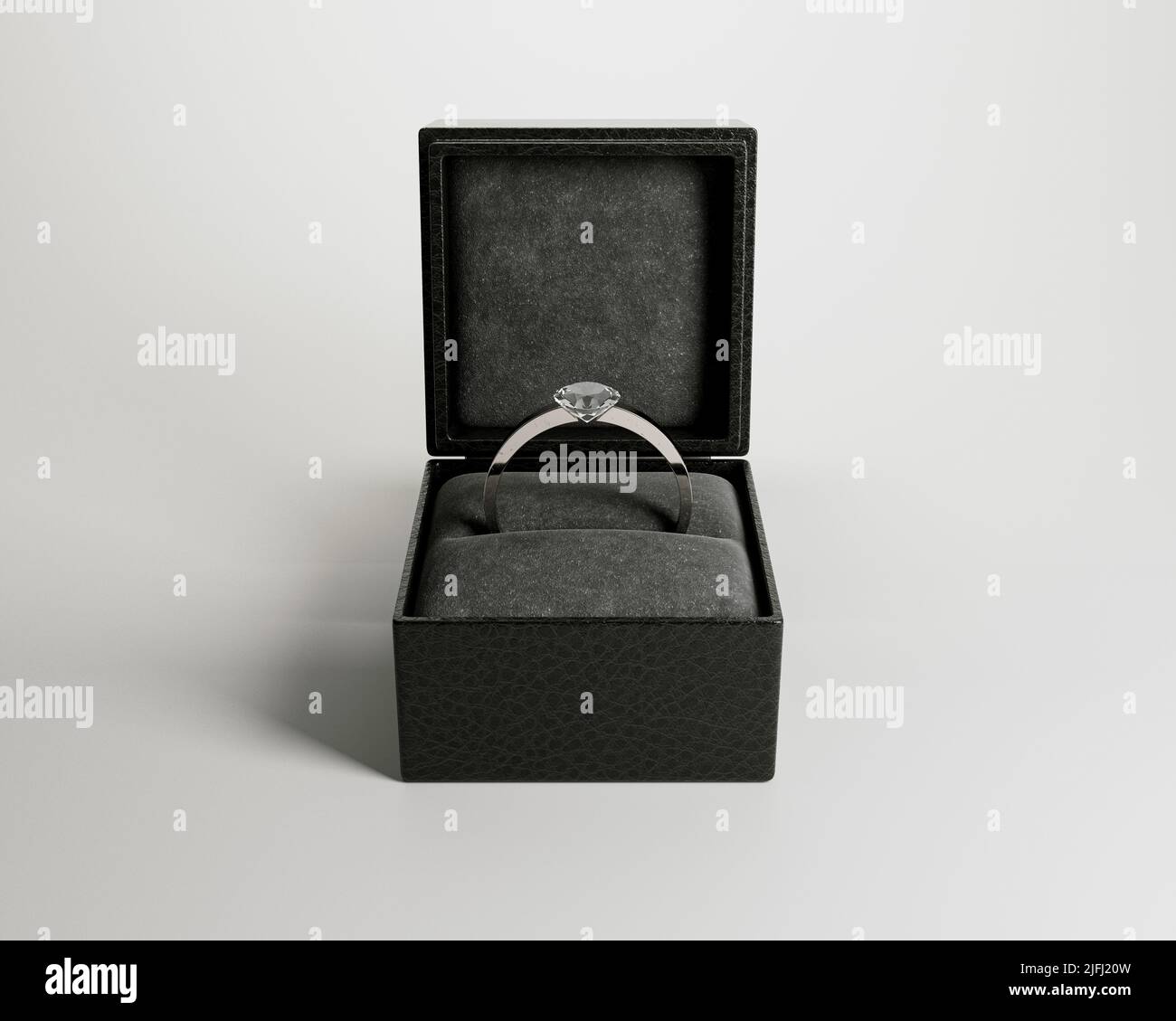 An open cube shaped black ring box with a silver engagement ring and ...
