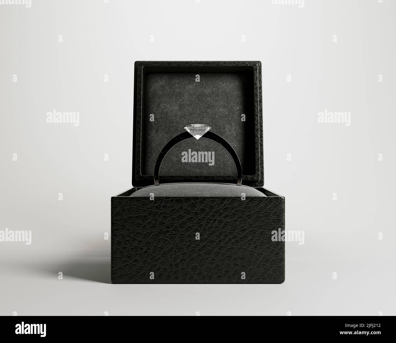 An open cube shaped black ring box with a silver engagement ring and ...