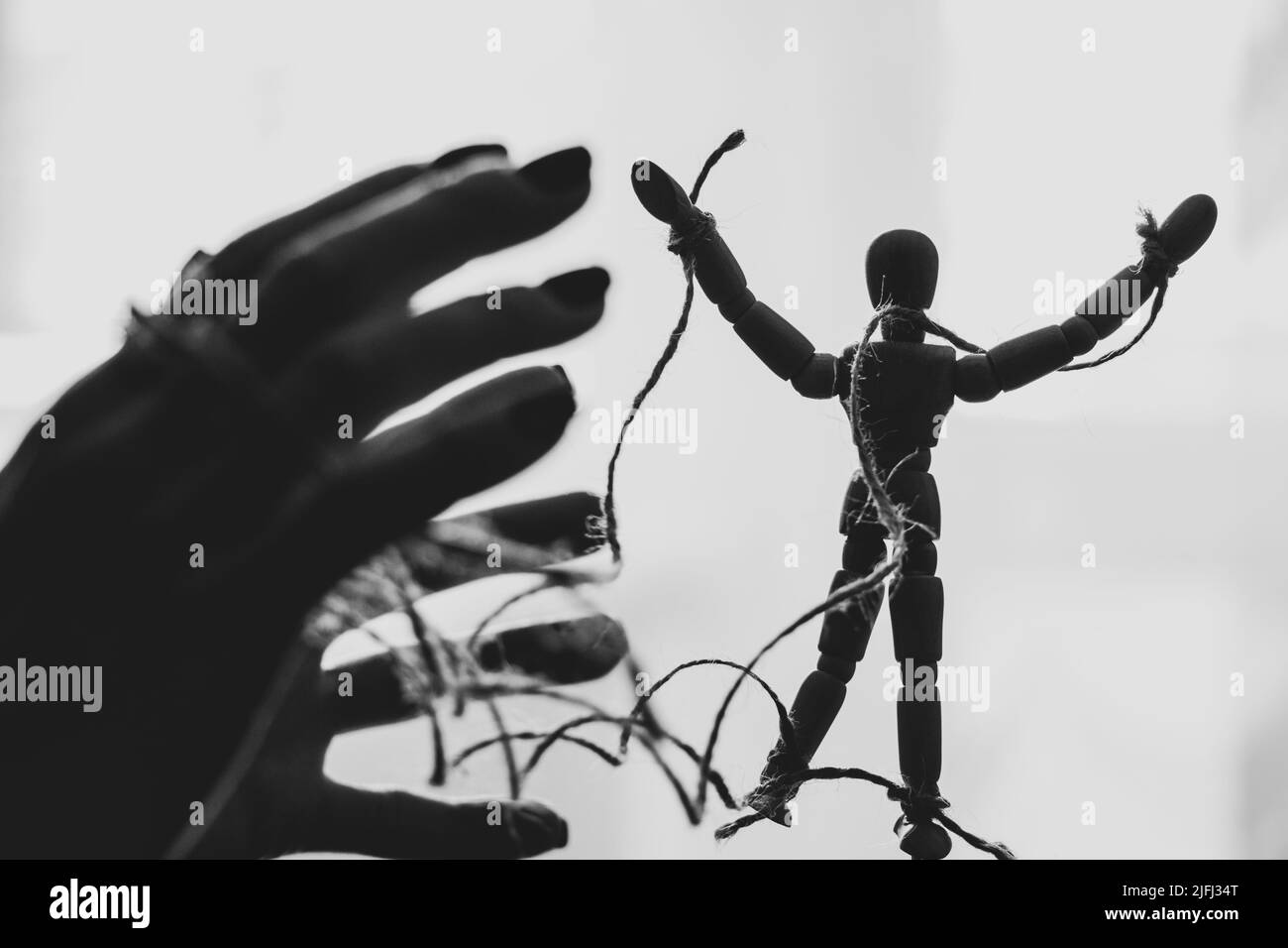 Wooden puppet tied with ropes to the puppeteer, manipulation of people ...