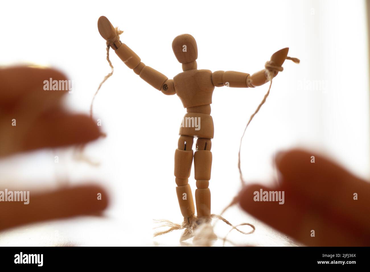 Wooden puppet tied with ropes to the puppeteer, manipulation of people ...