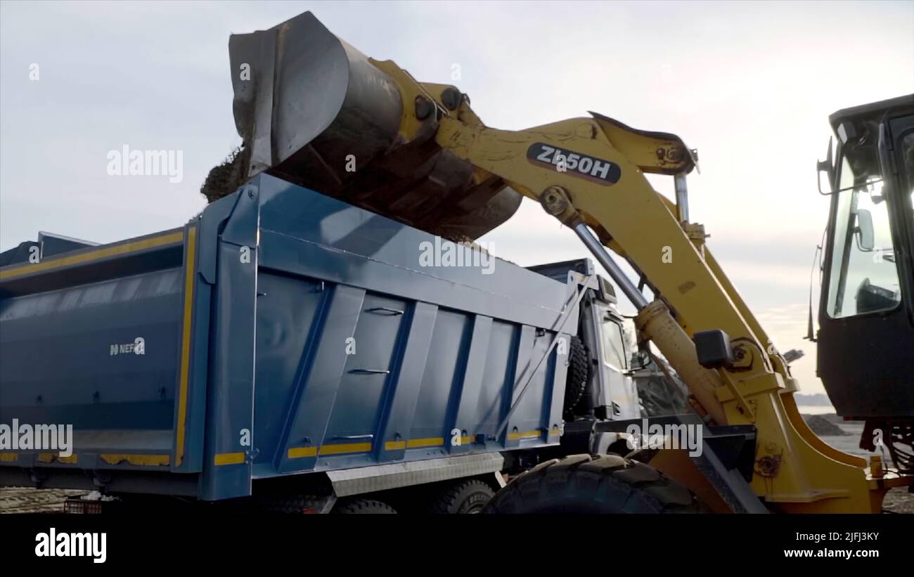 Side view of a mining truck with its bucket loaded with sand. Scene ...