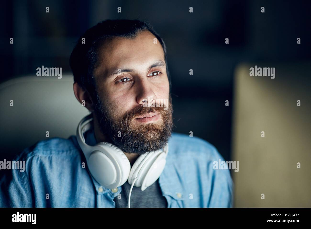 Close-up of thoughtful bearded computer programmer with headphones on ...