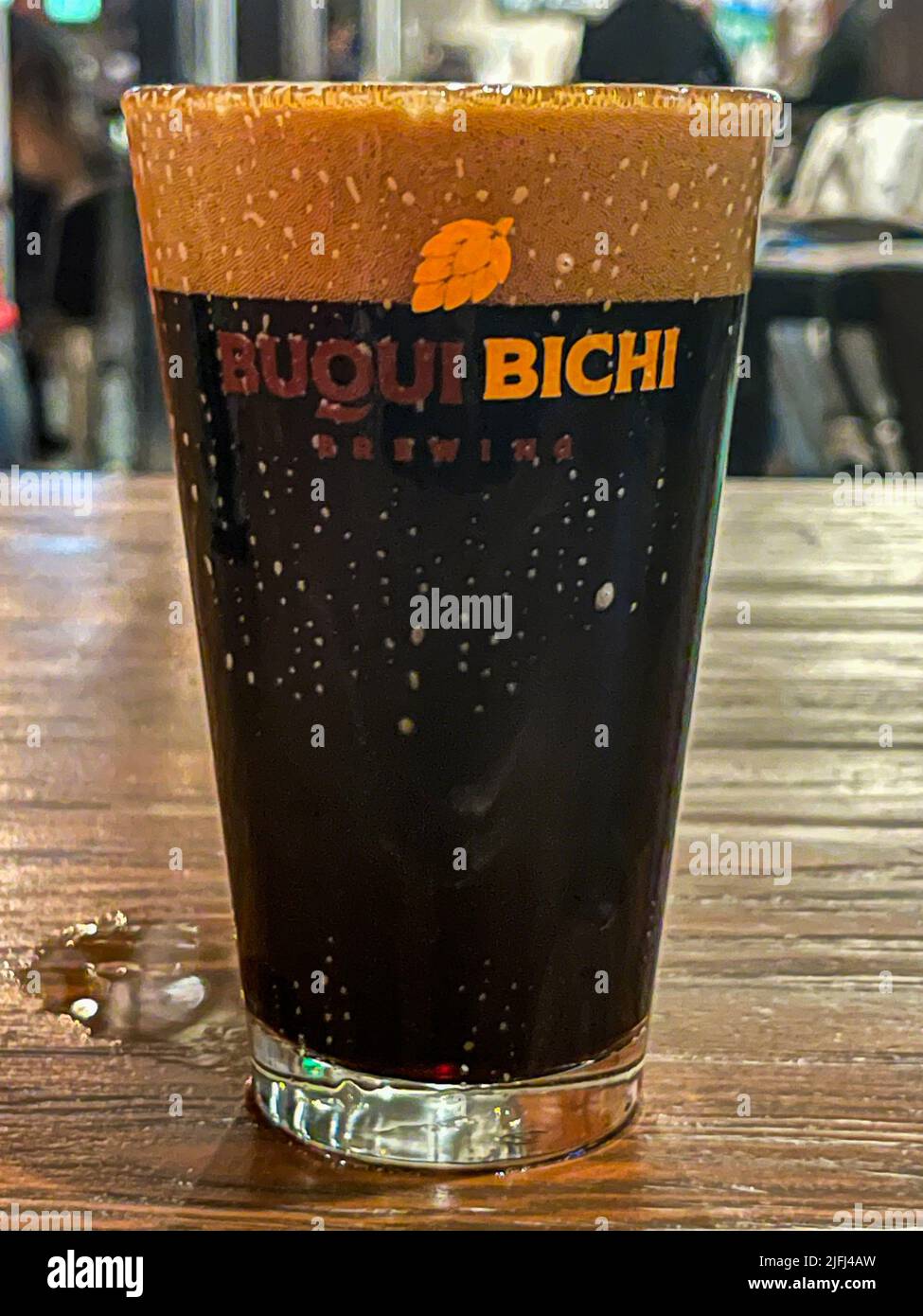 Glass glass with dark, brown Buqui Bichi craft beer on a wooden table ...