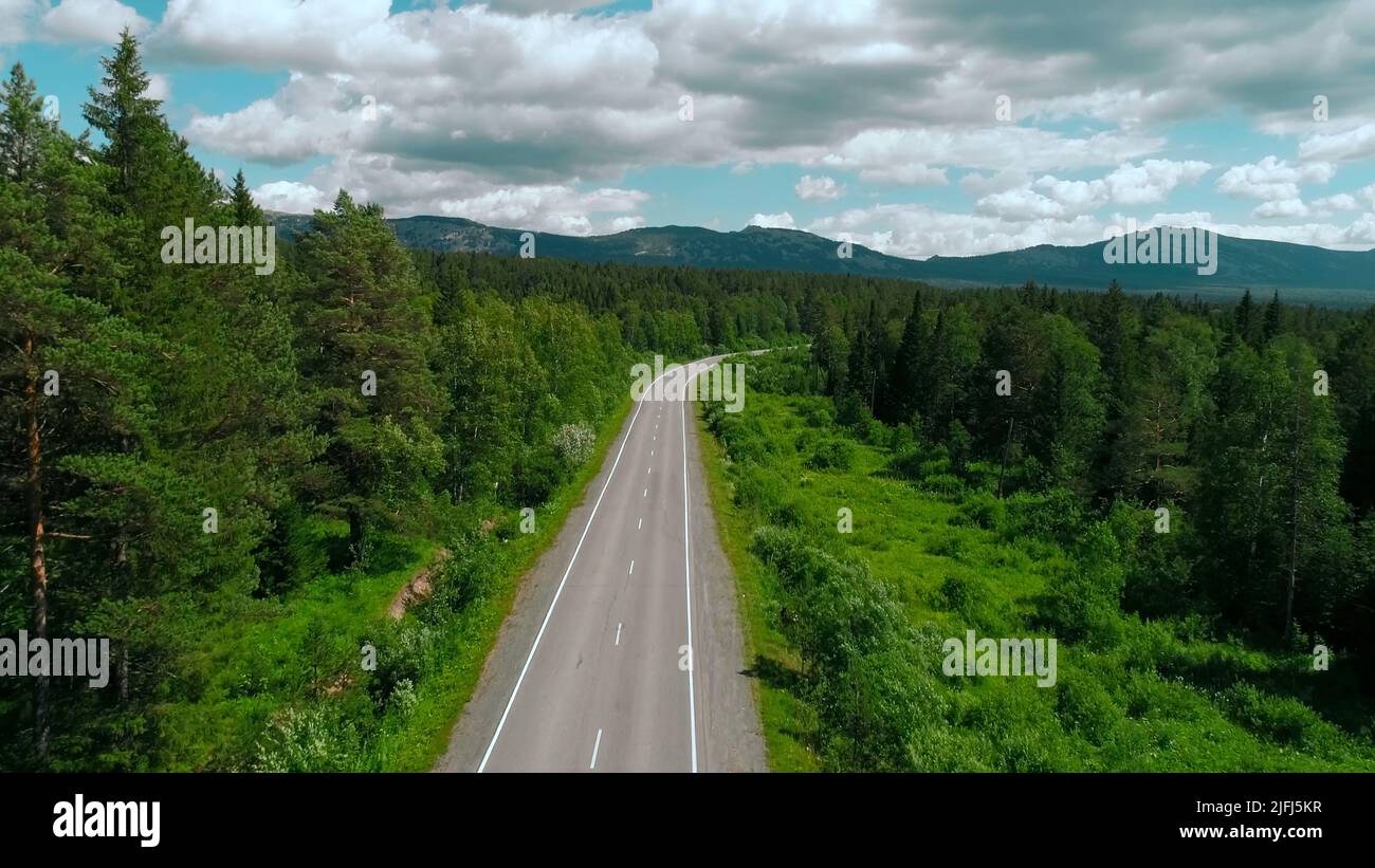 Aerial view of road across the forest on blue cloudy sky background ...
