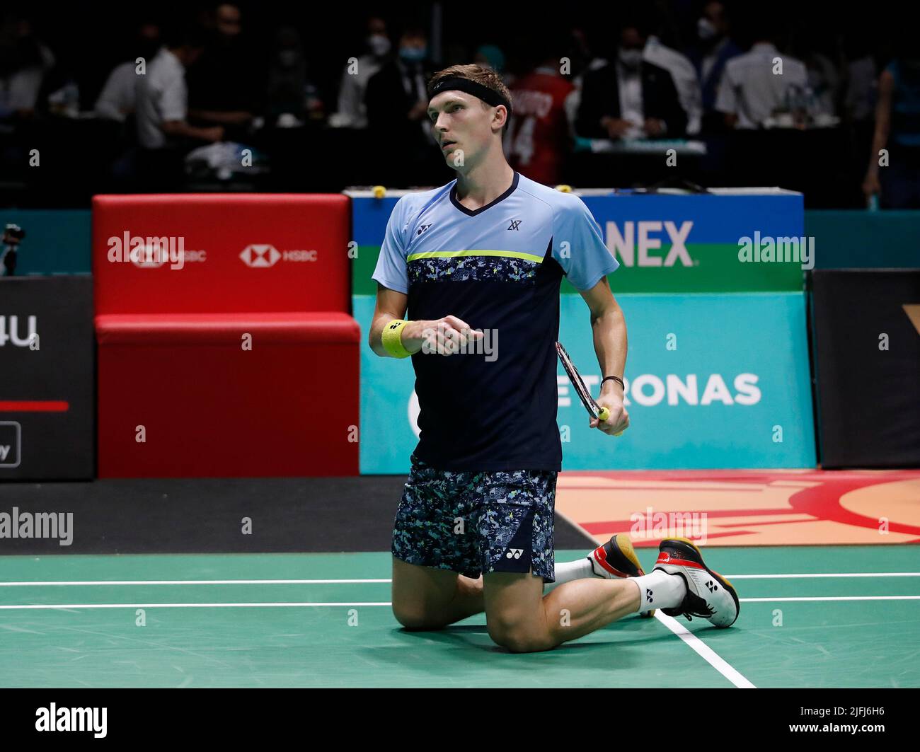 Viktor Axelsen of Denmark kneels as he celebrates after defeating Kento ...