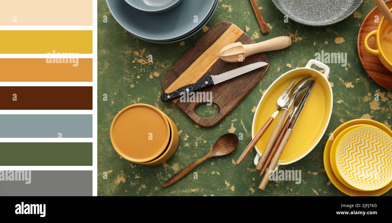 Different dinnerware and kitchen utensils on green background ...