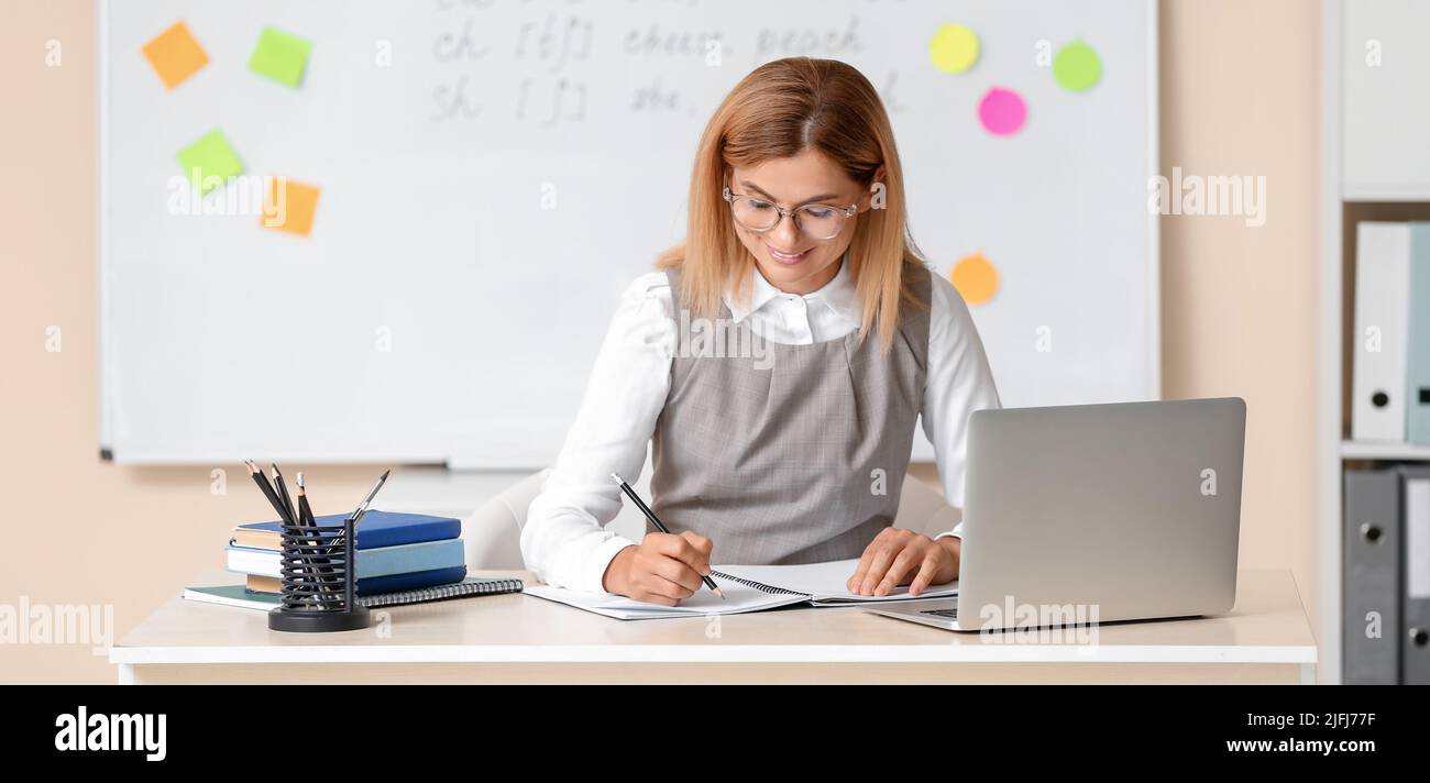 Female English teacher checking homework in classroom Stock Photo - Alamy