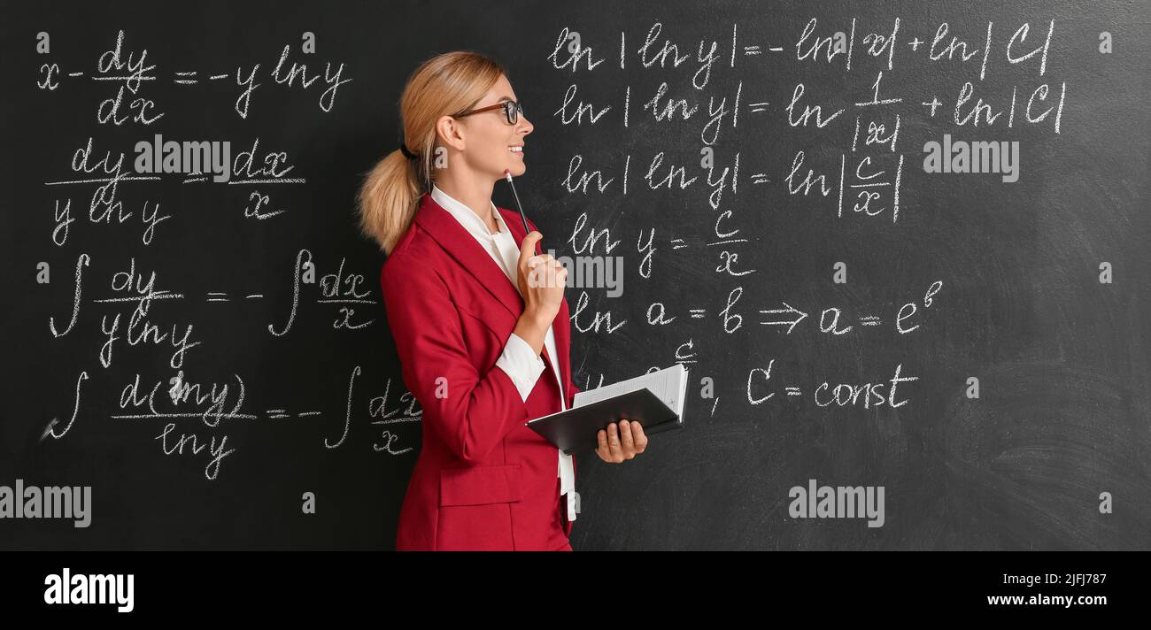 Beautiful maths teacher near blackboard in classroom Stock Photo - Alamy