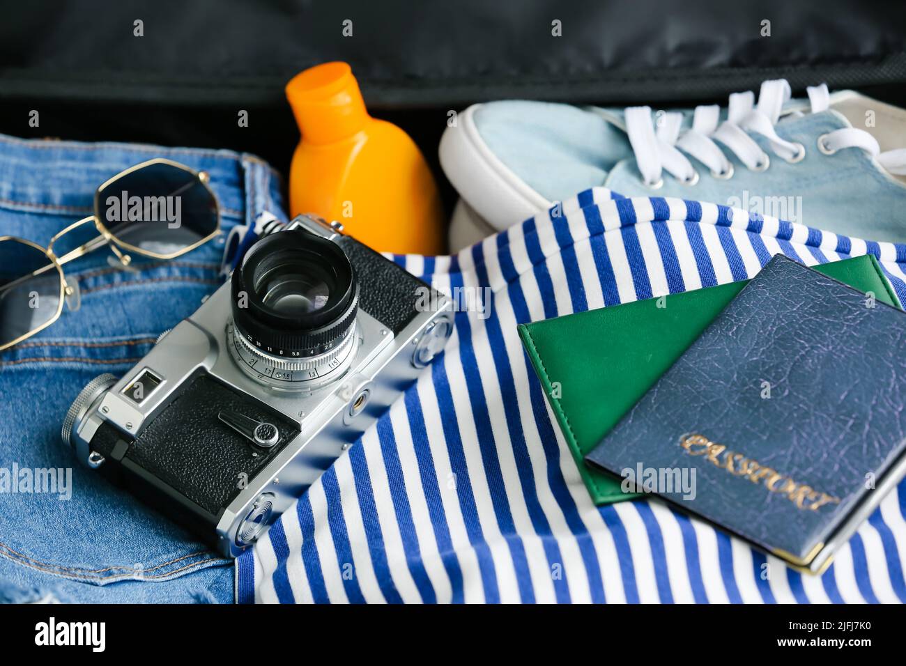 Passports and photo camera on female clothes in suitcase Stock Photo ...