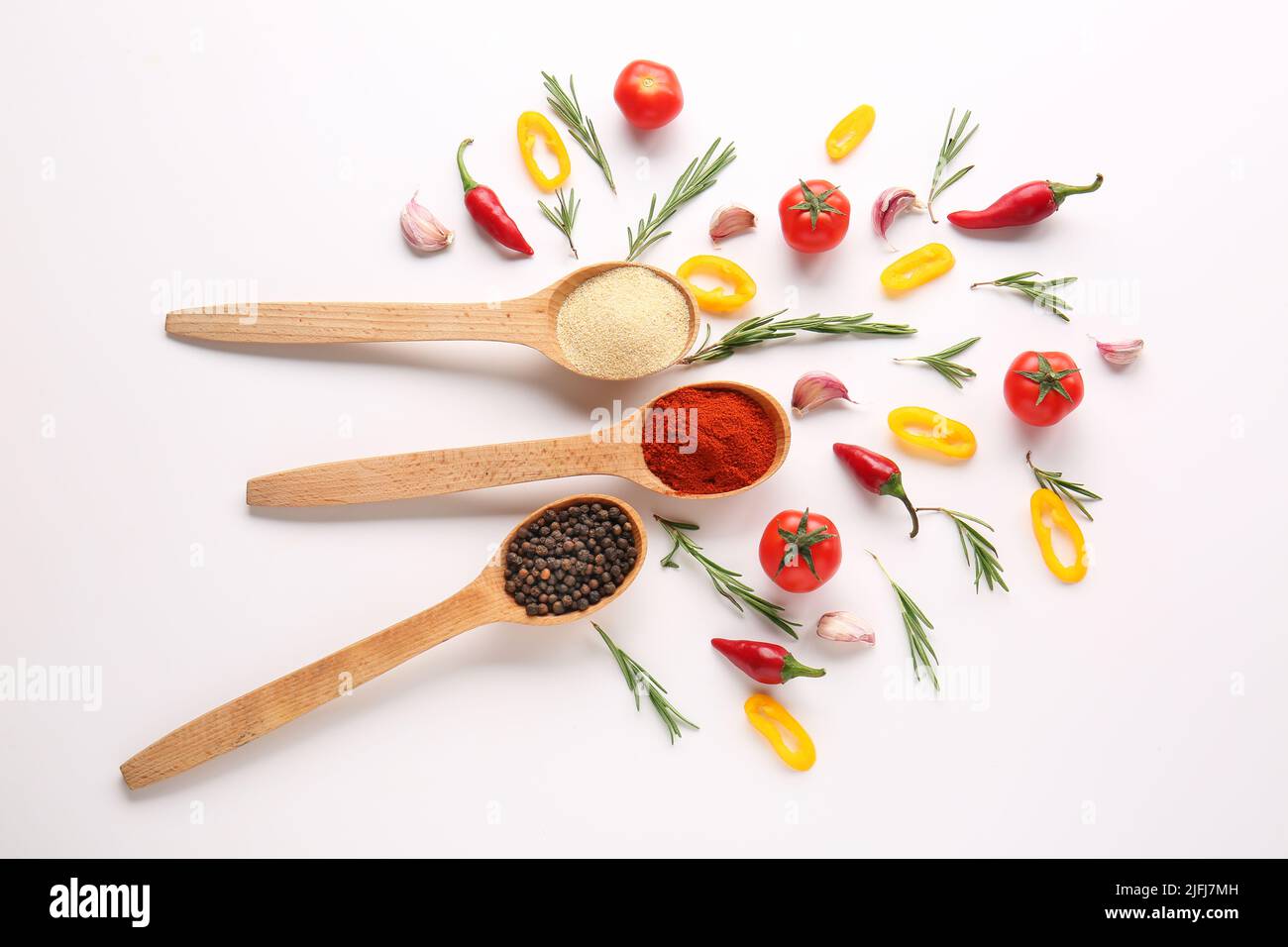 Wooden spoons with spices, herbs and vegetables on white background ...