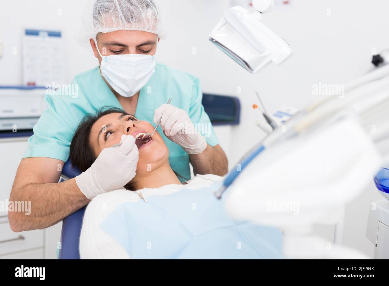 Dentist man examining a latin female patient teeth Stock Photo - Alamy