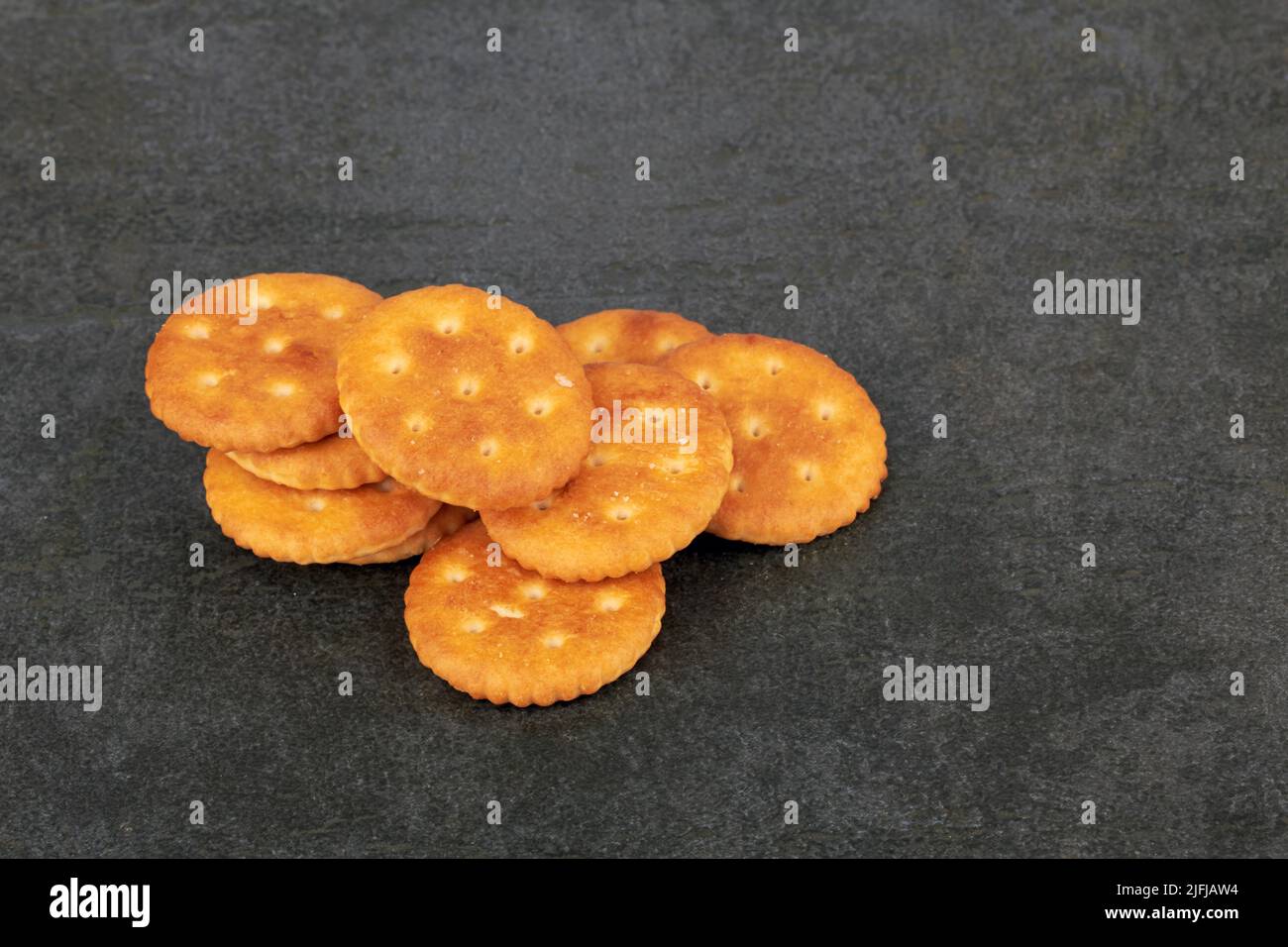 Round salted snack cracker on black stone surface Stock Photo - Alamy
