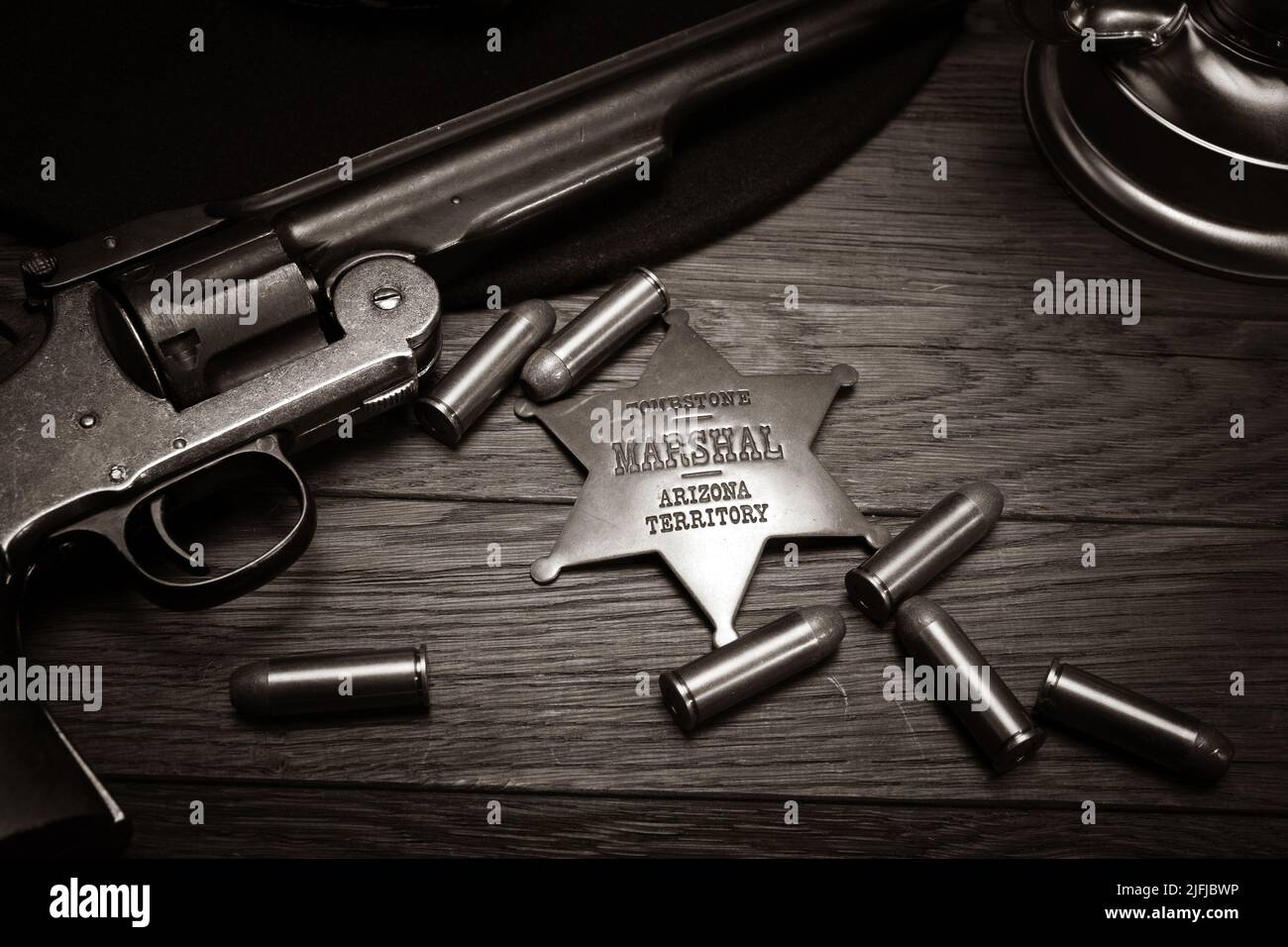 Old west. Marshals badge and revolver with cartridges on wooden table ...